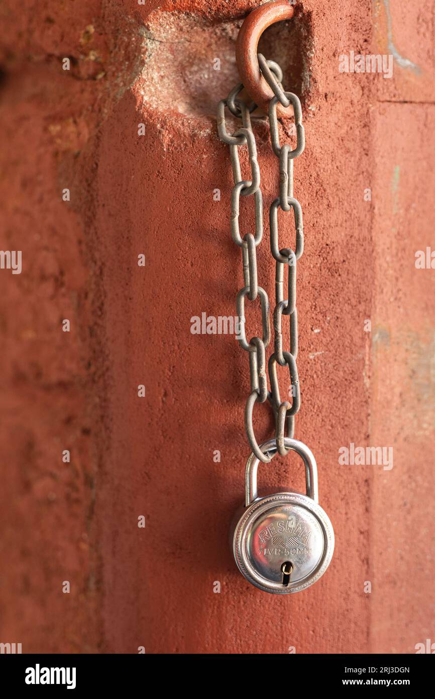 An isolated image of a shiny silver padlock and chain hanging from an ...