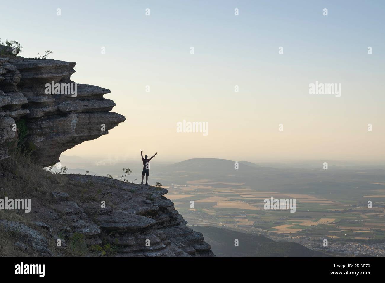 A vibrant image of a person standing atop a majestic mountain with arms ...
