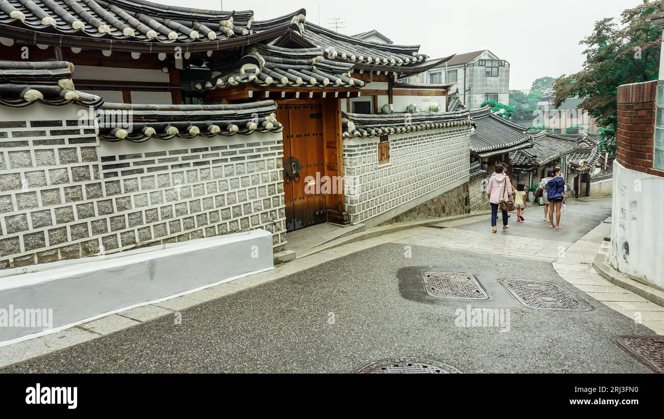 A group of people walking along a busy street in Bukchon Hanok Village ...
