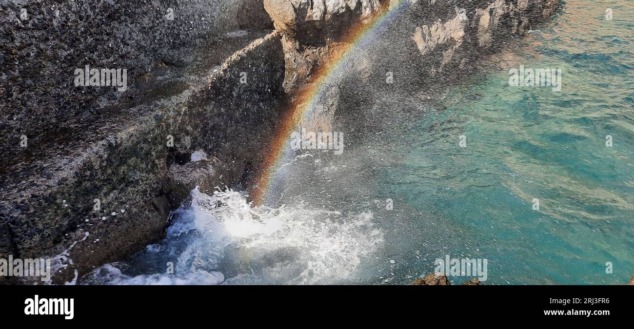 A rainbow emerges when it rains. rainbow with splashing water of a sea ...