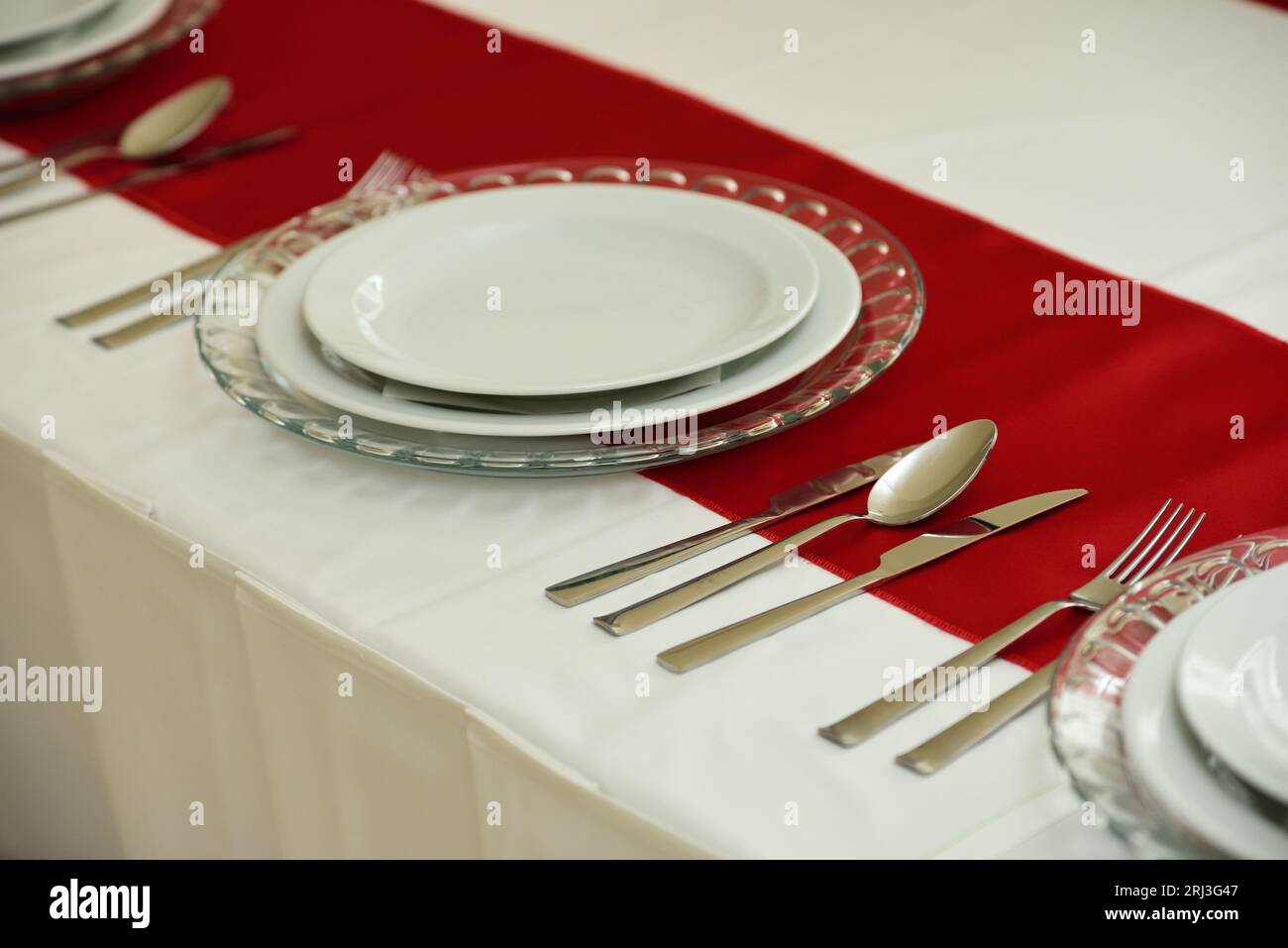 A rectangular dining table with matching silverware and plates set up ...