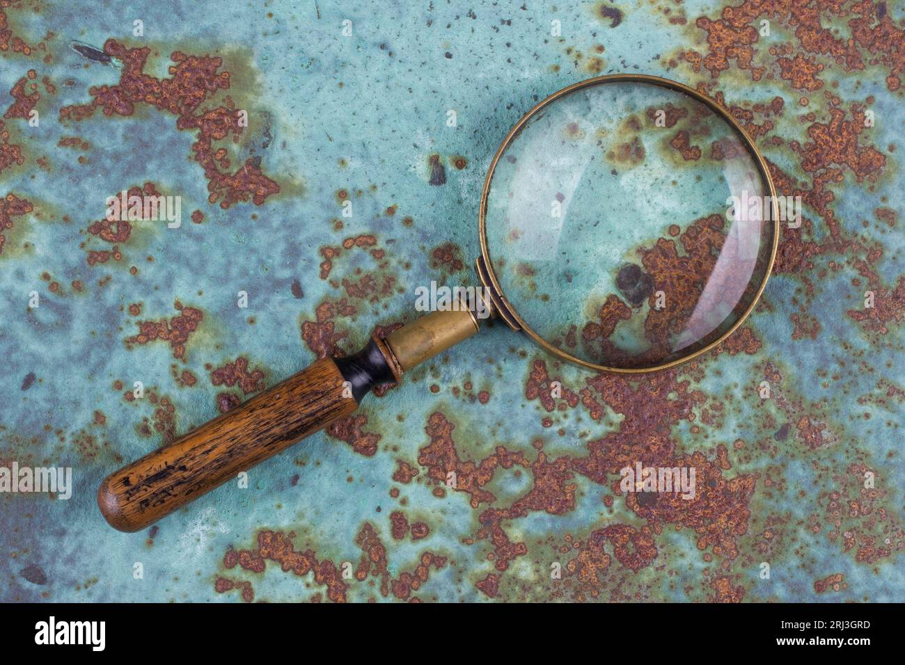 Vintage magnifying glass on rusty metal surface coated with corrosion ...