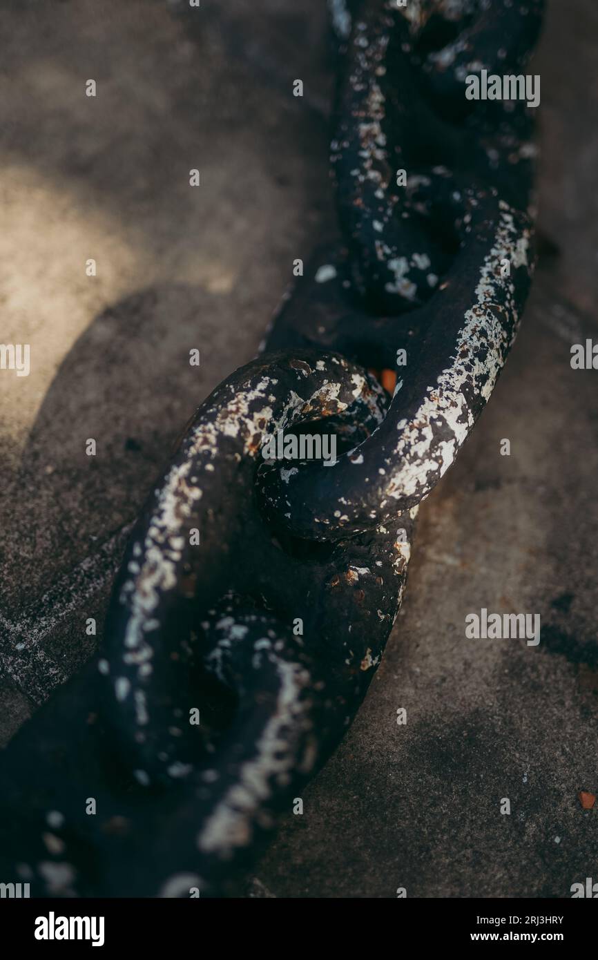 An aged black chain with chipped paint, put on a grey concrete Stock ...