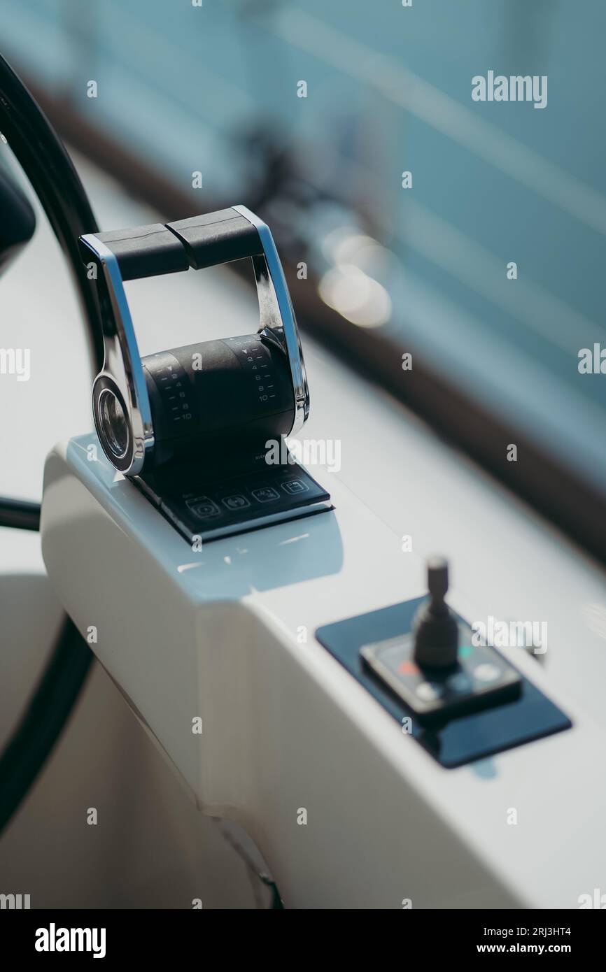 A close-up shot of a boat's steering wheel, with control and dashboard ...