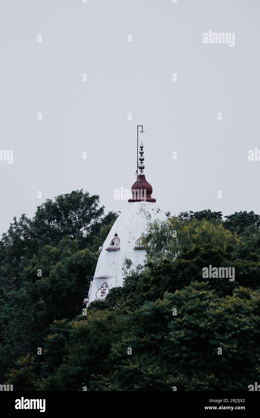 An image of an ancient Indian temple tower, situated in a lush green ...
