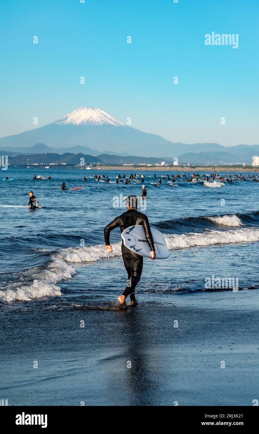 A vertical shot of Surfing in Enoshima, Japan with Mount Fuji in the ...
