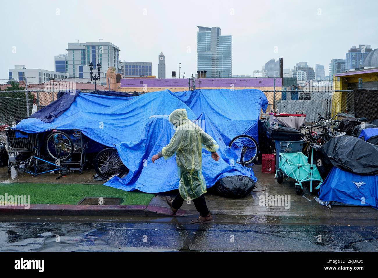 Homeless people use plastic tarps to shield themselves from a light ...