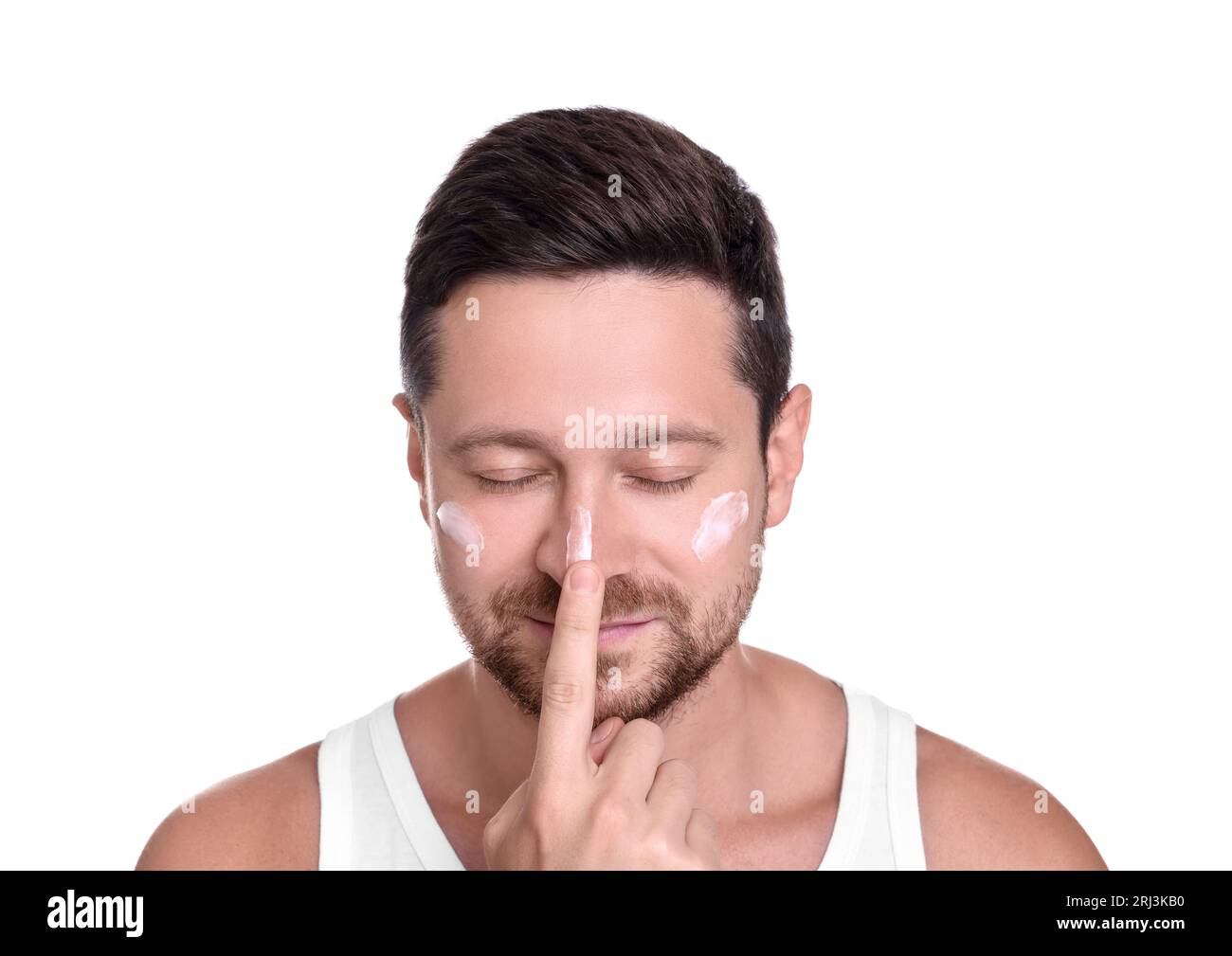 Man applying sun protection cream onto his face against white ...