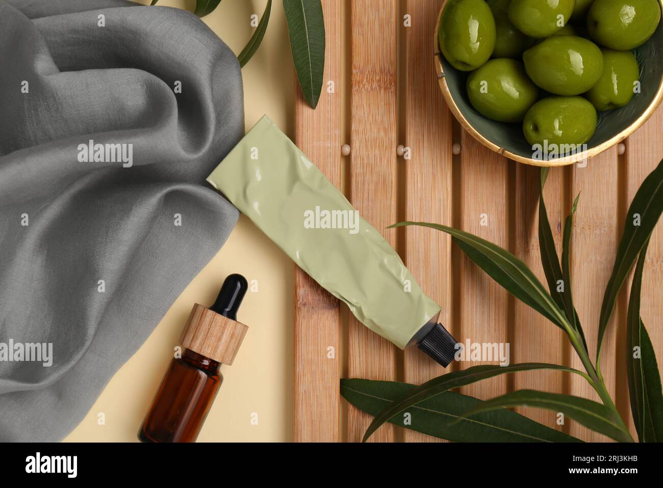 Cosmetic products with olive essential oil and leaves beige background ...