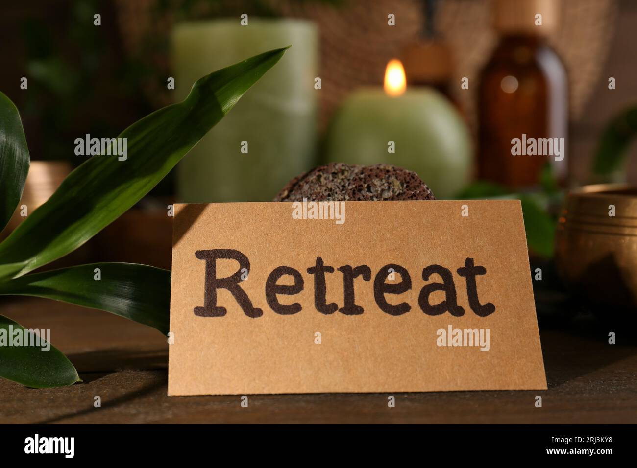 Card with word Retreat and green leaf on blurred background, closeup ...