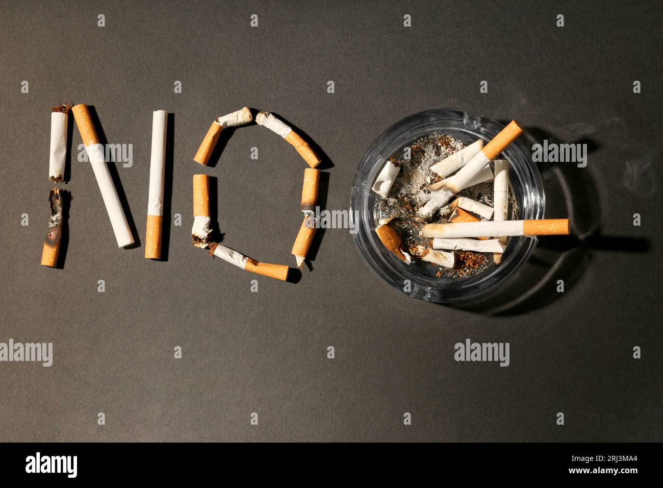 Word No made with burnt cigarettes and ashtray on black table, flat lay ...