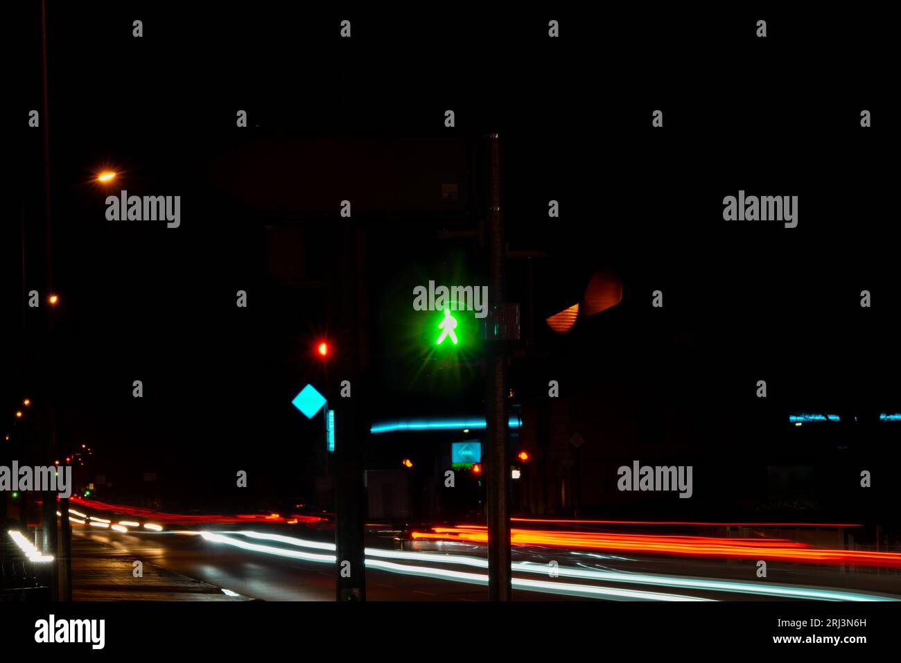 A vivid nighttime scene features a vibrant green traffic light ...
