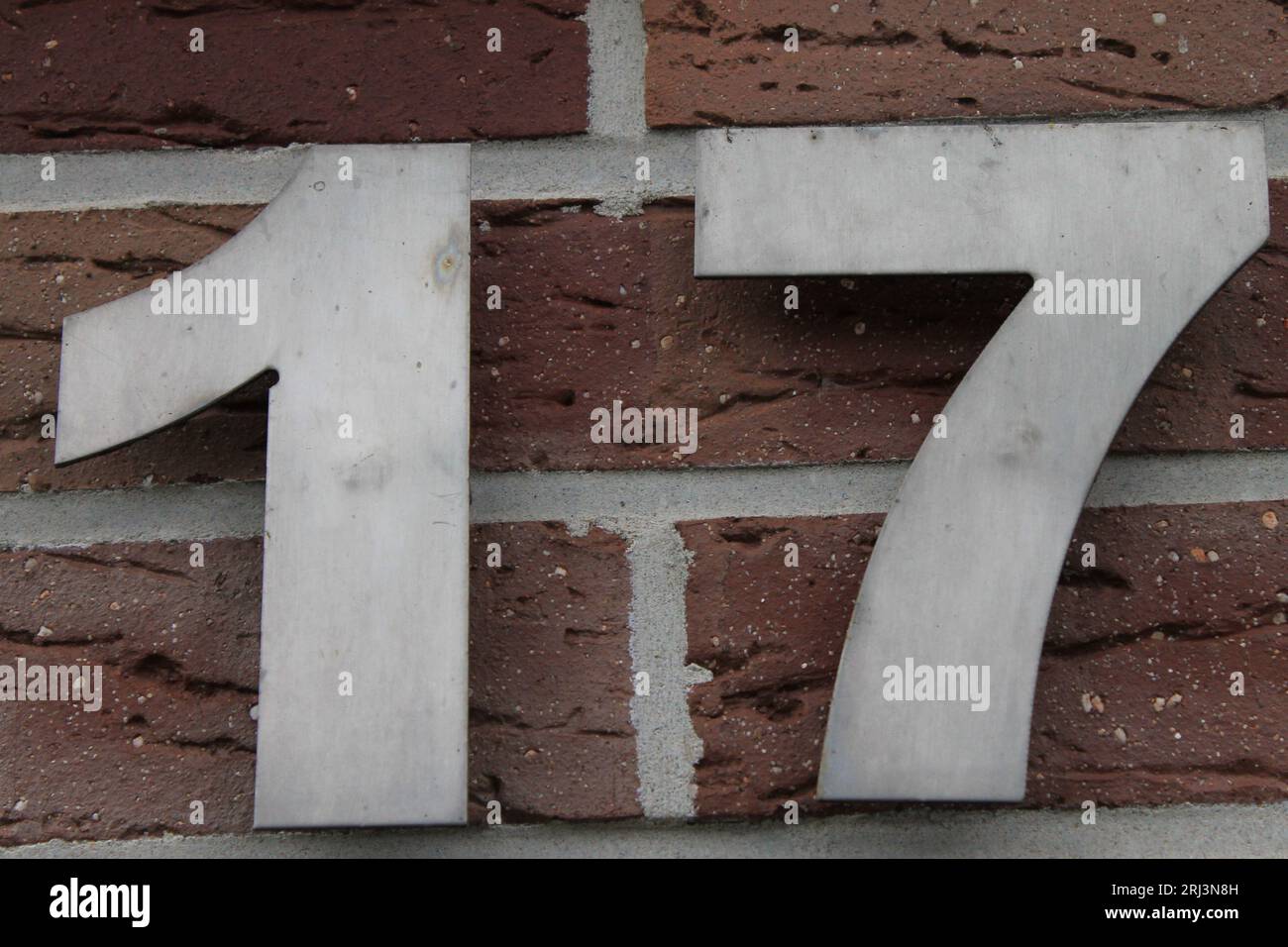 An image of a red painted house number 17 affixed to a brick wall Stock ...