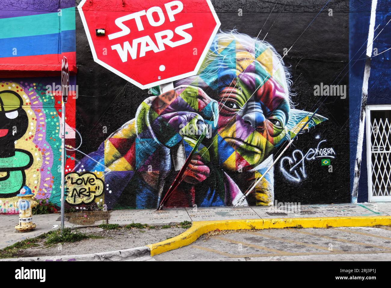 A street wall with colorful graffiti art of a cartoon Yoda character ...