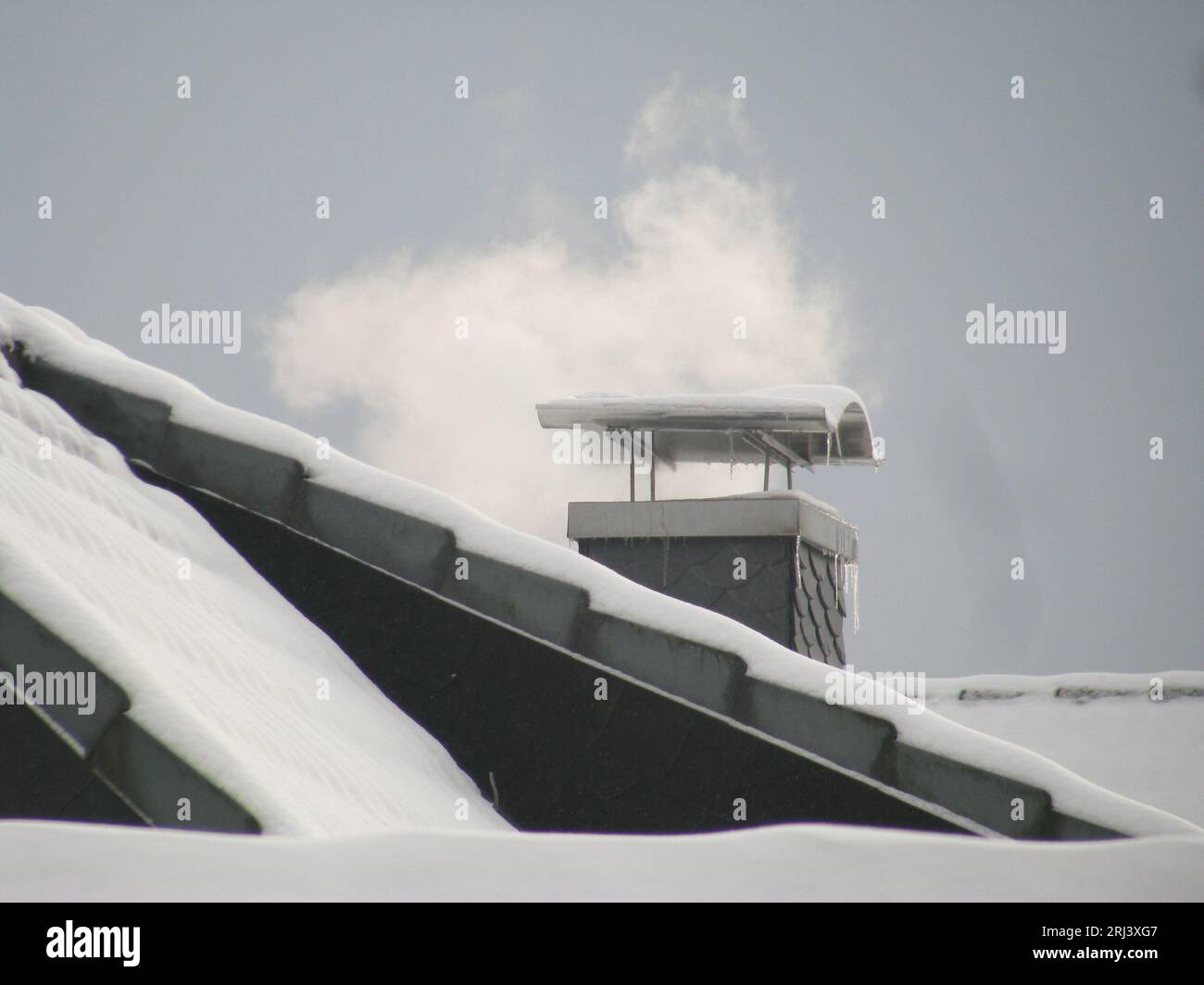 a residential rooftop covered in snow, with a vertical chimney pipe ...
