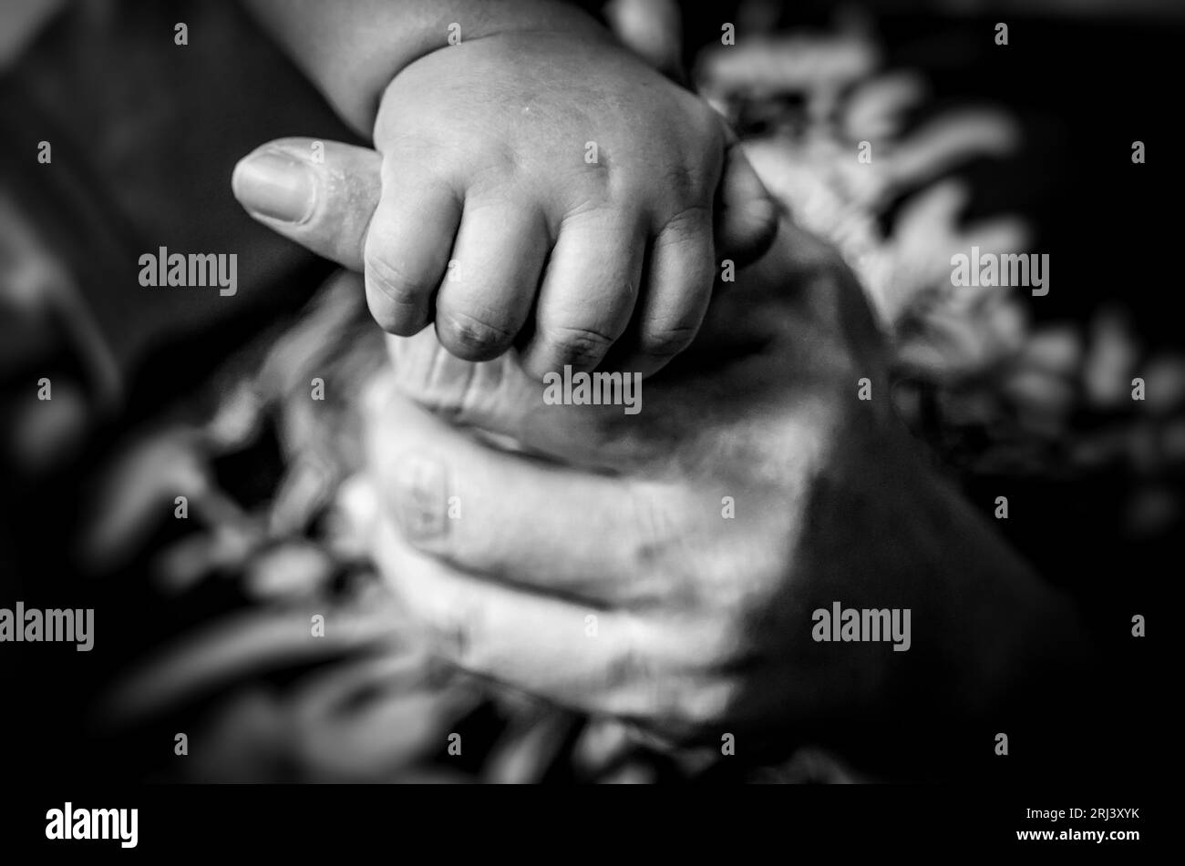 A black and white close-up of two hands joining, as one hand gently ...