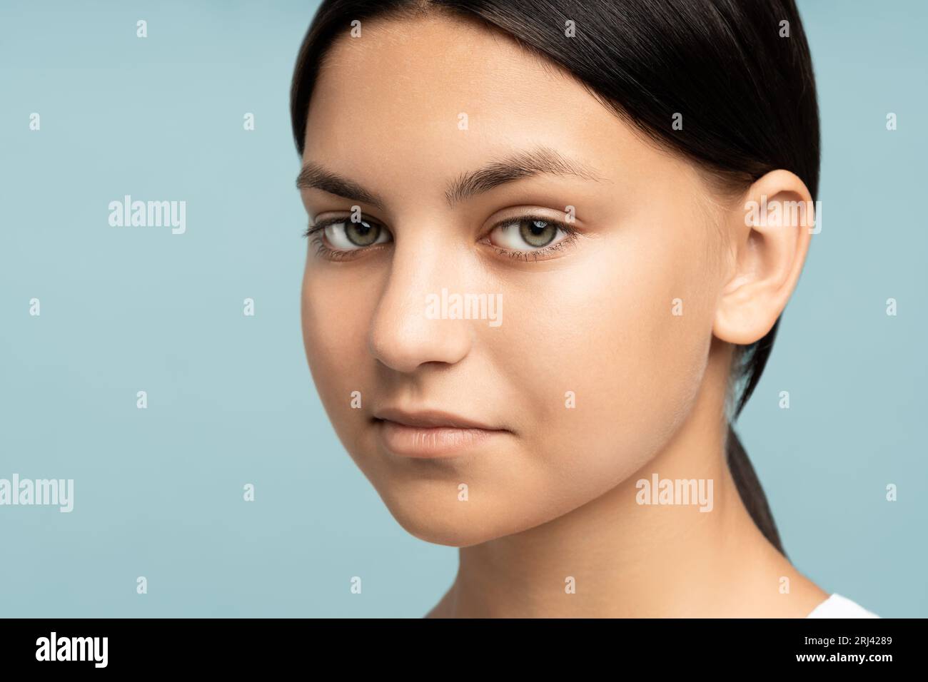 Teenage girl looking at camera, close up. Portrait of girl slight smile ...