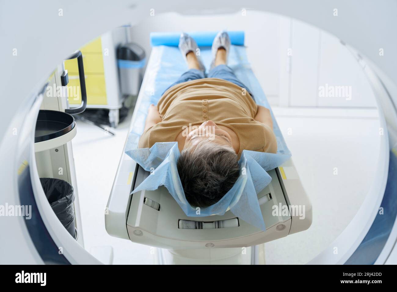 Female patient lying on table and entering CT machine during ...
