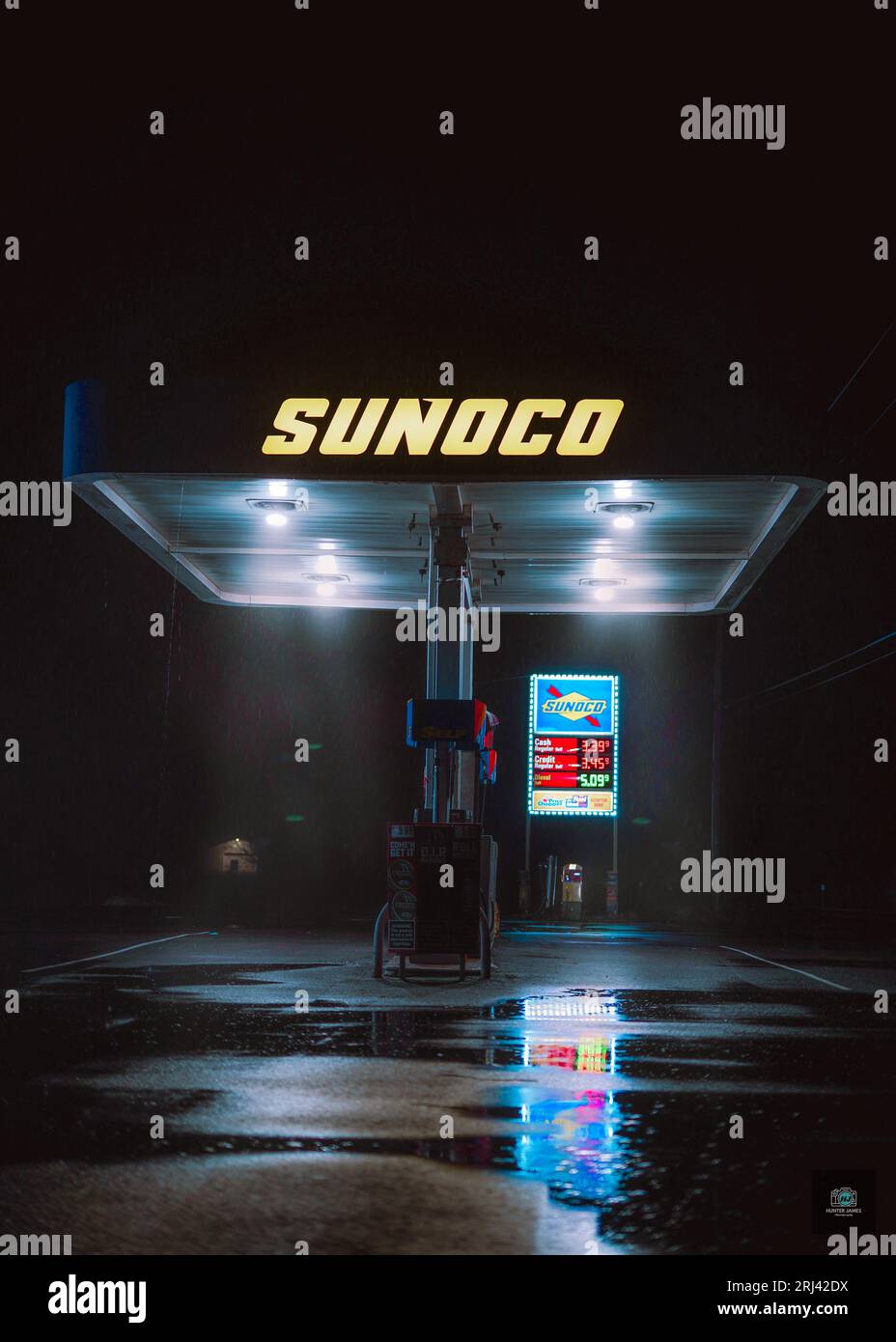 A bright illuminated sign displaying the Sunoco logo reflected in a ...