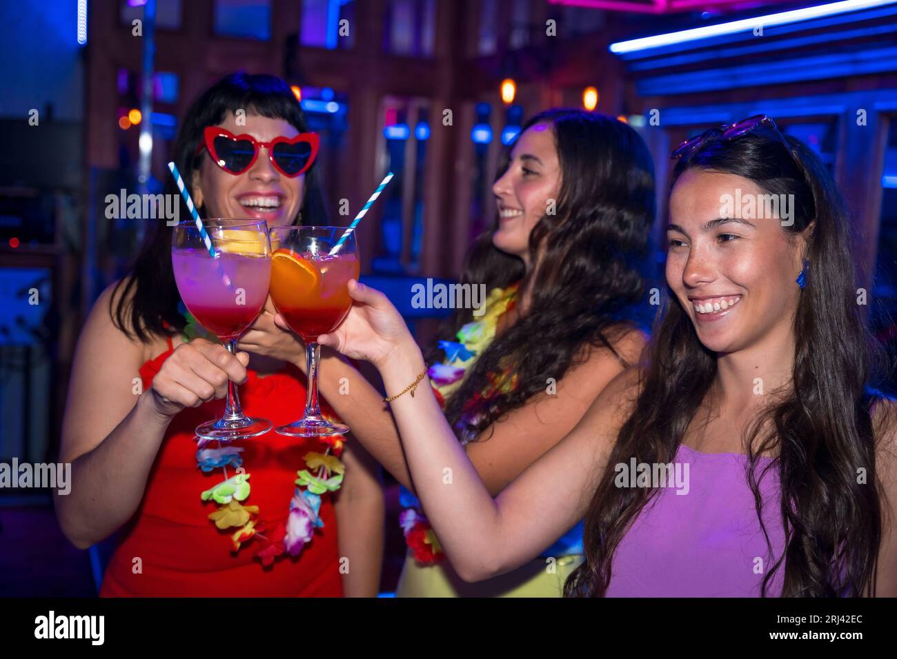 A shallow focus of three cheerful women drinking cocktails and ...