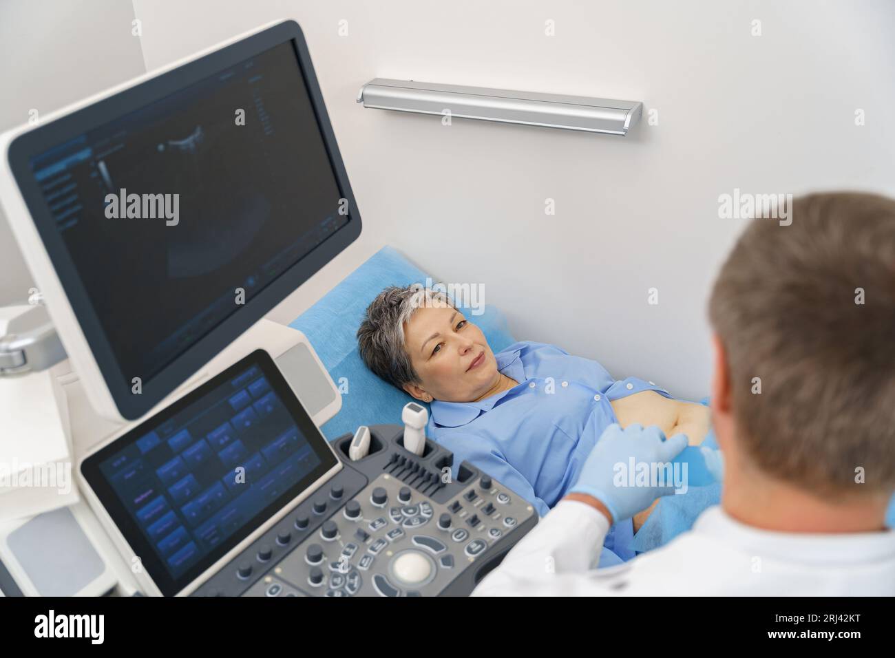 Male sonographer doing abdominal ultrasound scanning for patient in ...