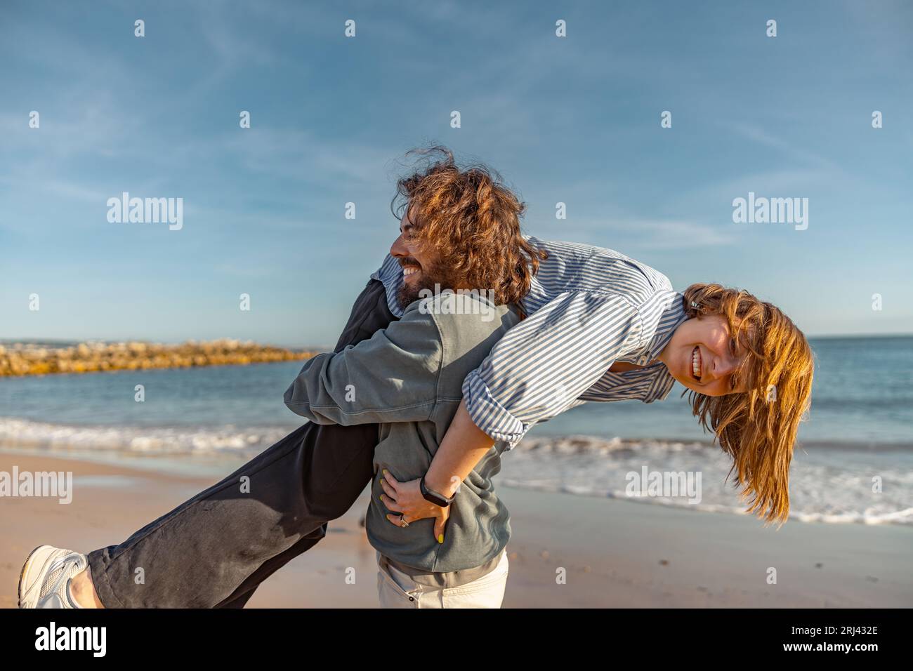Smilng couple in love fool around while walking along the beach on ...
