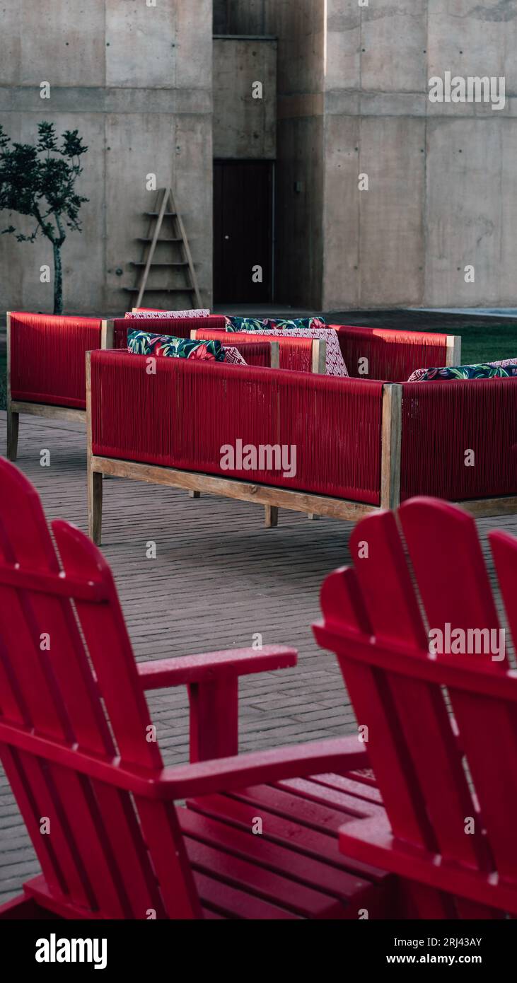 A collection of red patio chairs arranged in a cluster on an outdoor ...