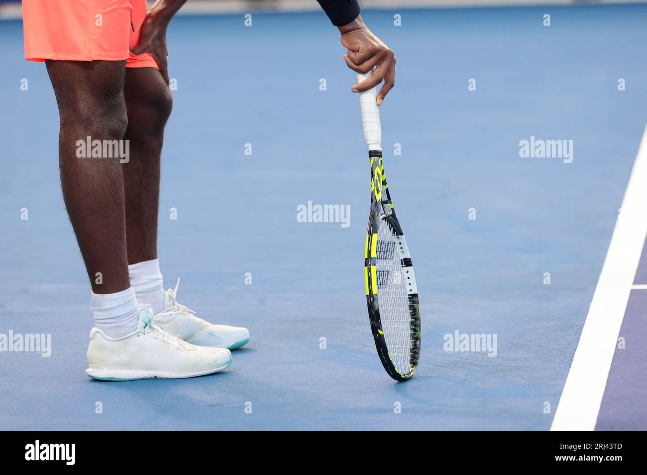 A male wearing activewear is standing atop a tennis court with a tennis ...