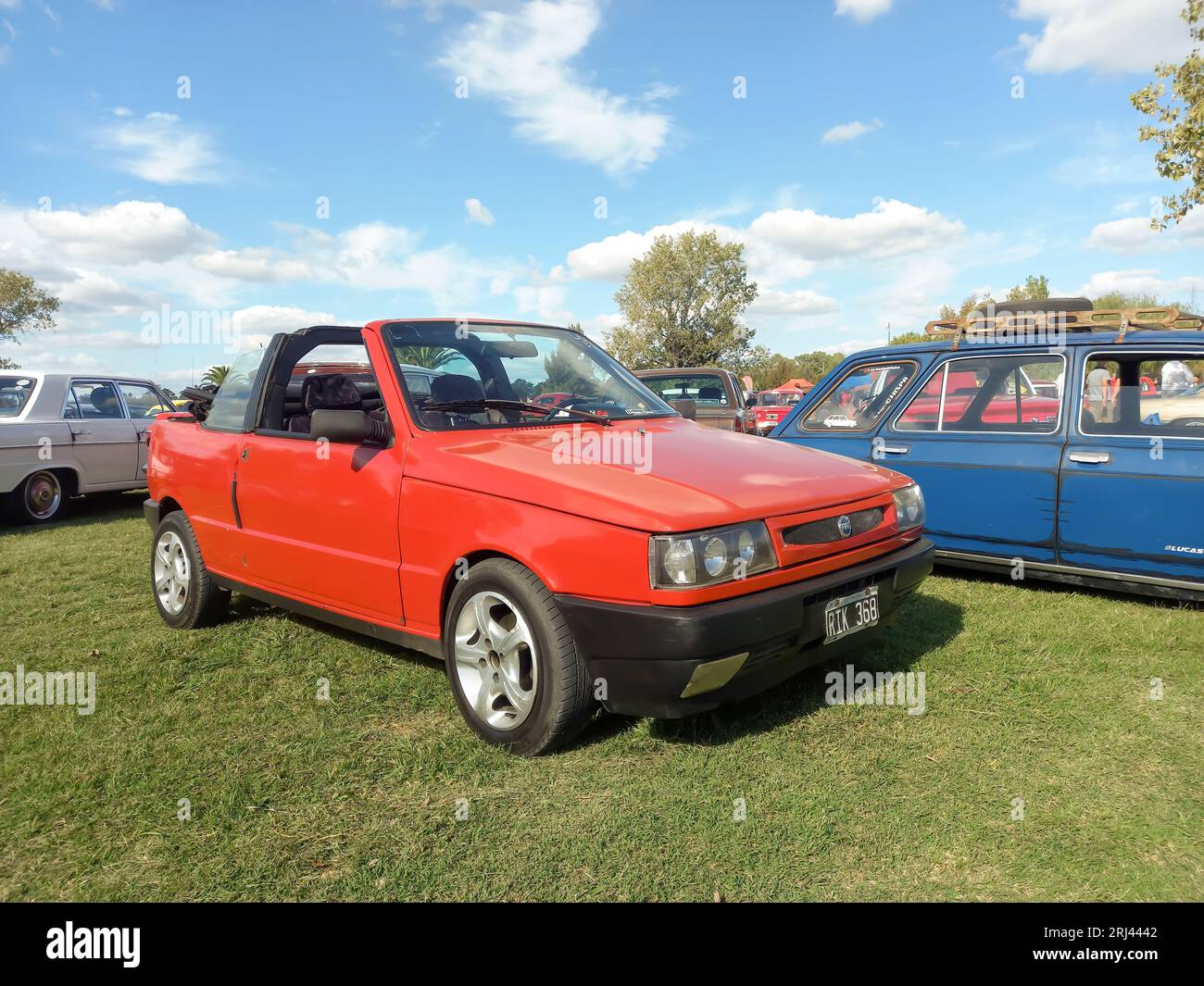 Old red Fiat Uno cabriolet on the lawn. Nature, grass, trees. CAACMACH ...