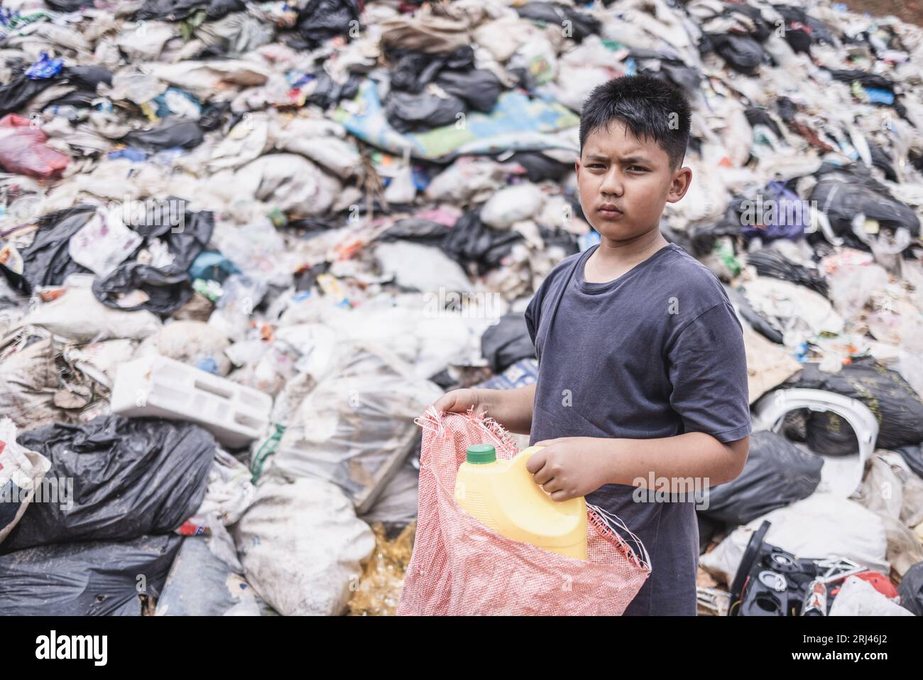 Sad child on garbage dump, boy picking up trash for sale, concept of ...