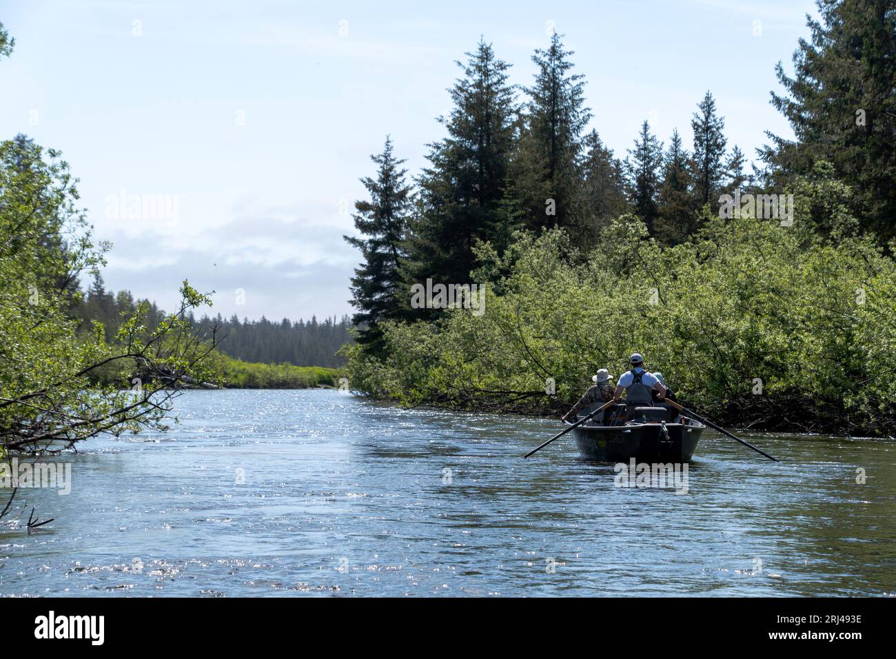 Two people paddling a boat on a river surrounded by greenery in Yakutat ...