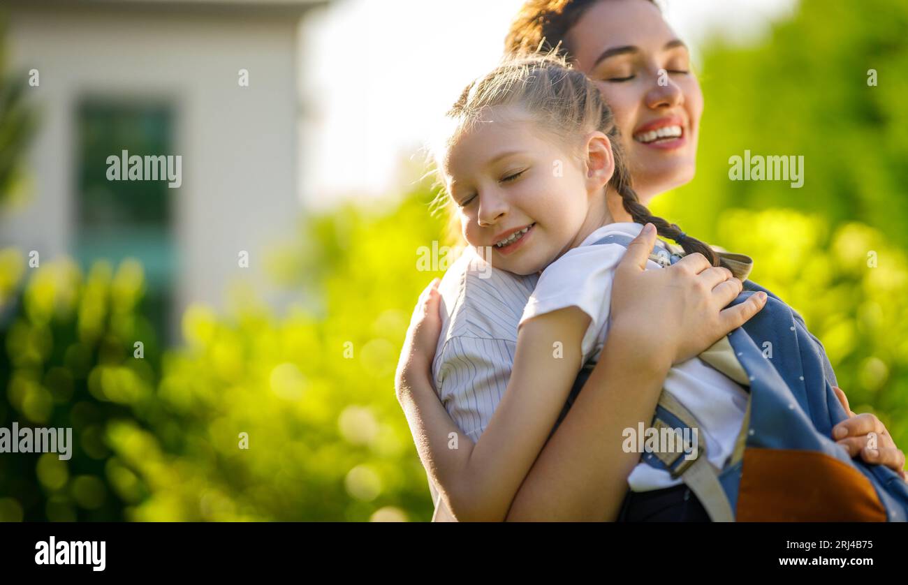 Parent and kid going to school. Woman and girl with backpack behind the ...