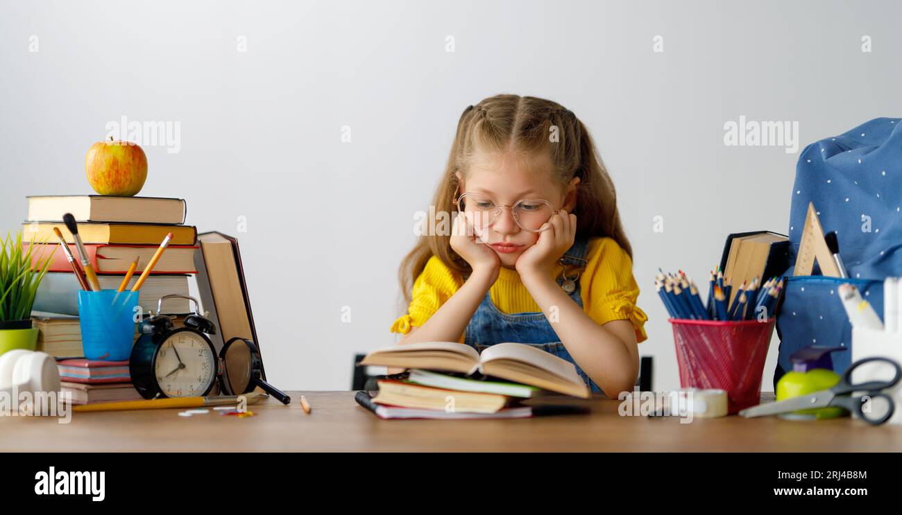 Back to school. Thinking child is sitting at desk. Girl doing homework ...