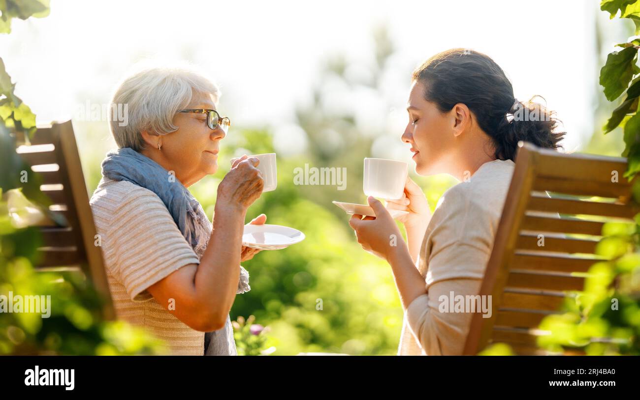 Happy young woman and her mother drinking tea in summer morning. Family ...