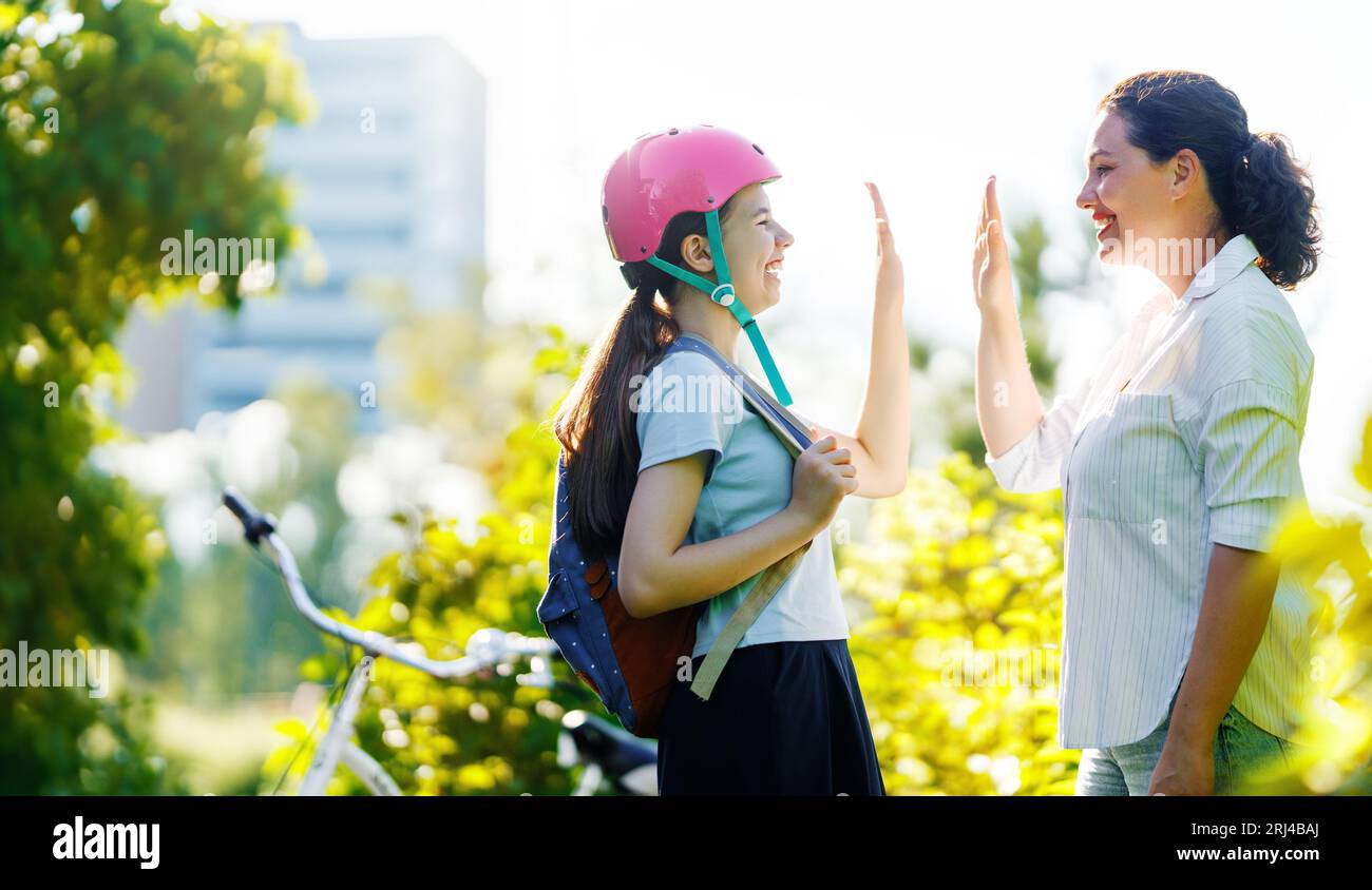 Girl in safety helmet with bike and backpack. Happy child with mother ...