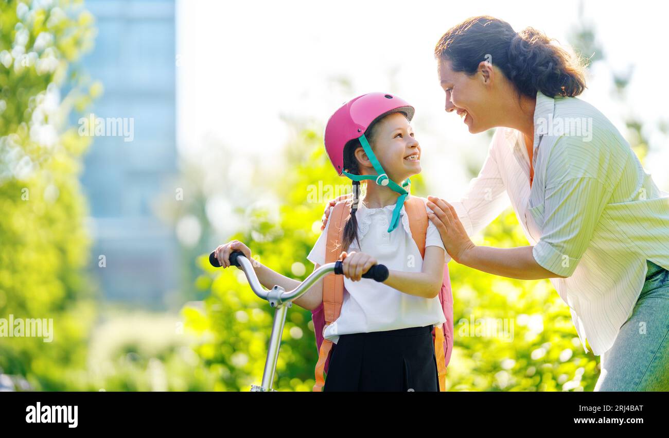 Girl in safety helmet with bike and backpack. Happy child with mother ...