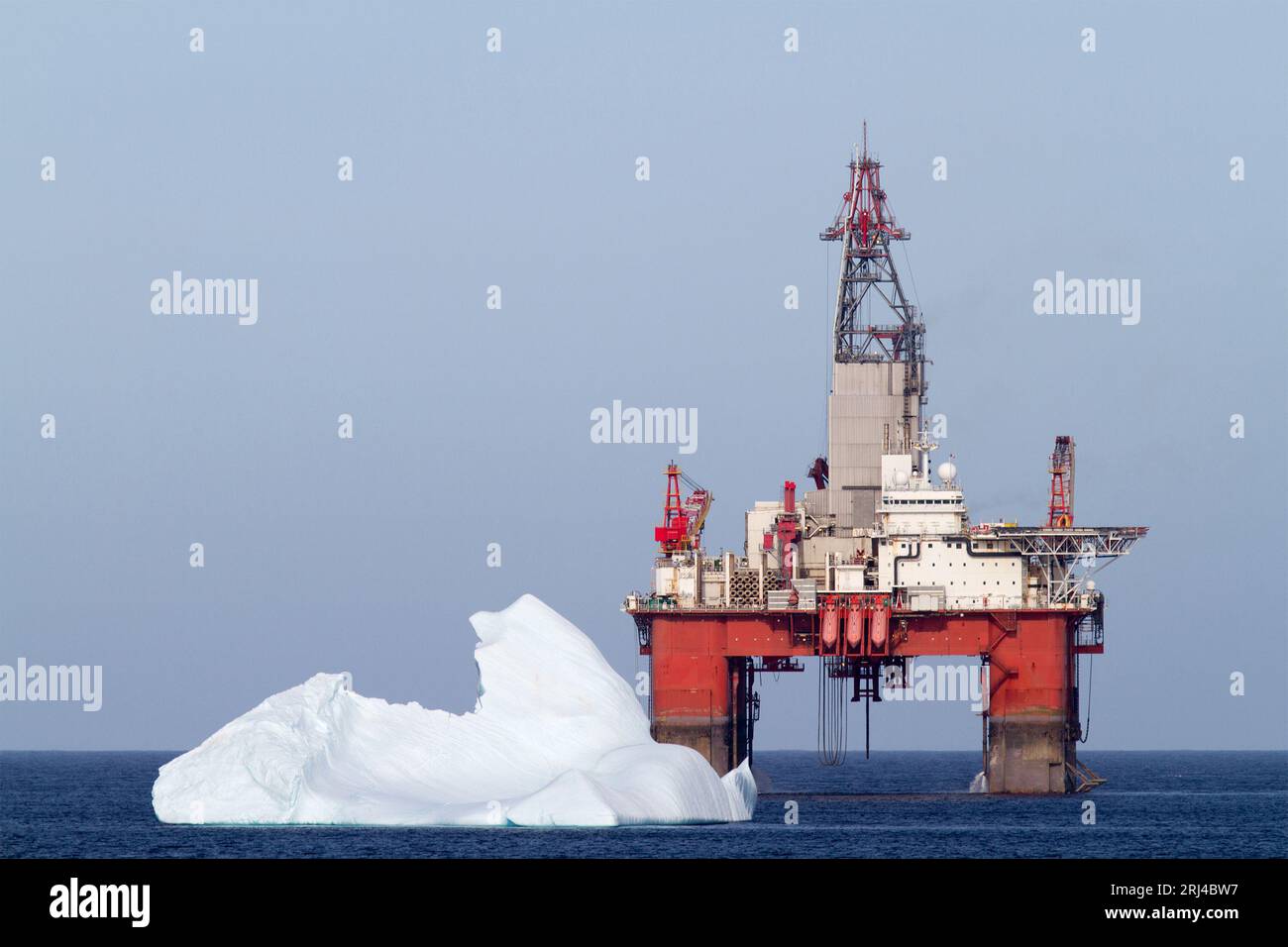 An offshore oil rig on the surface of blue water in the ocean with a ...