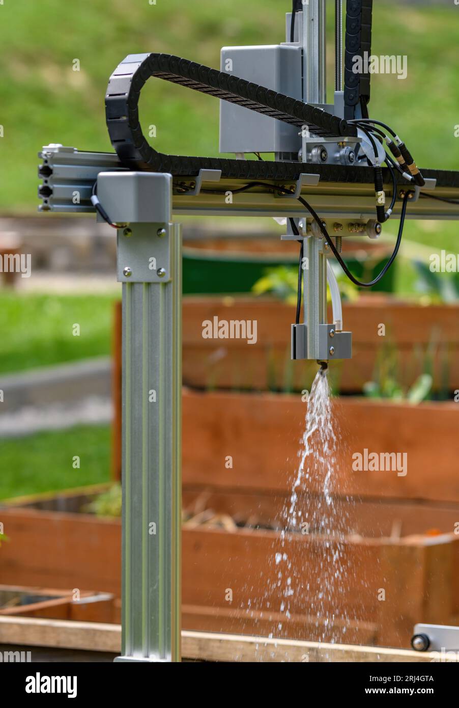 A Plant growing robot Farmbot watering plants on a raised bed in garden ...