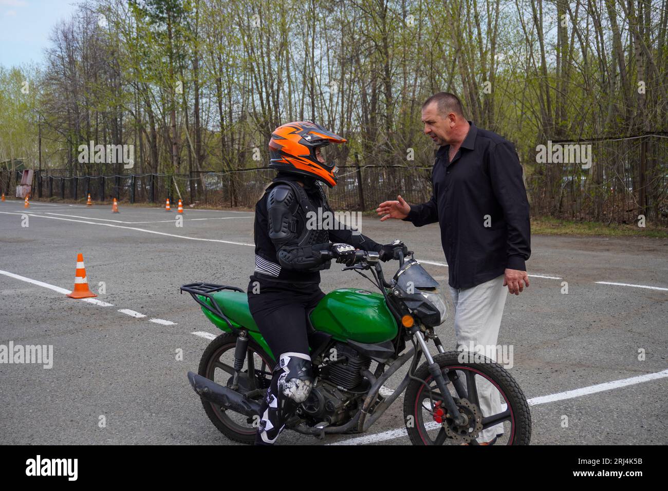 A young woman is learning to ride a motorbike in a motorcycle school ...