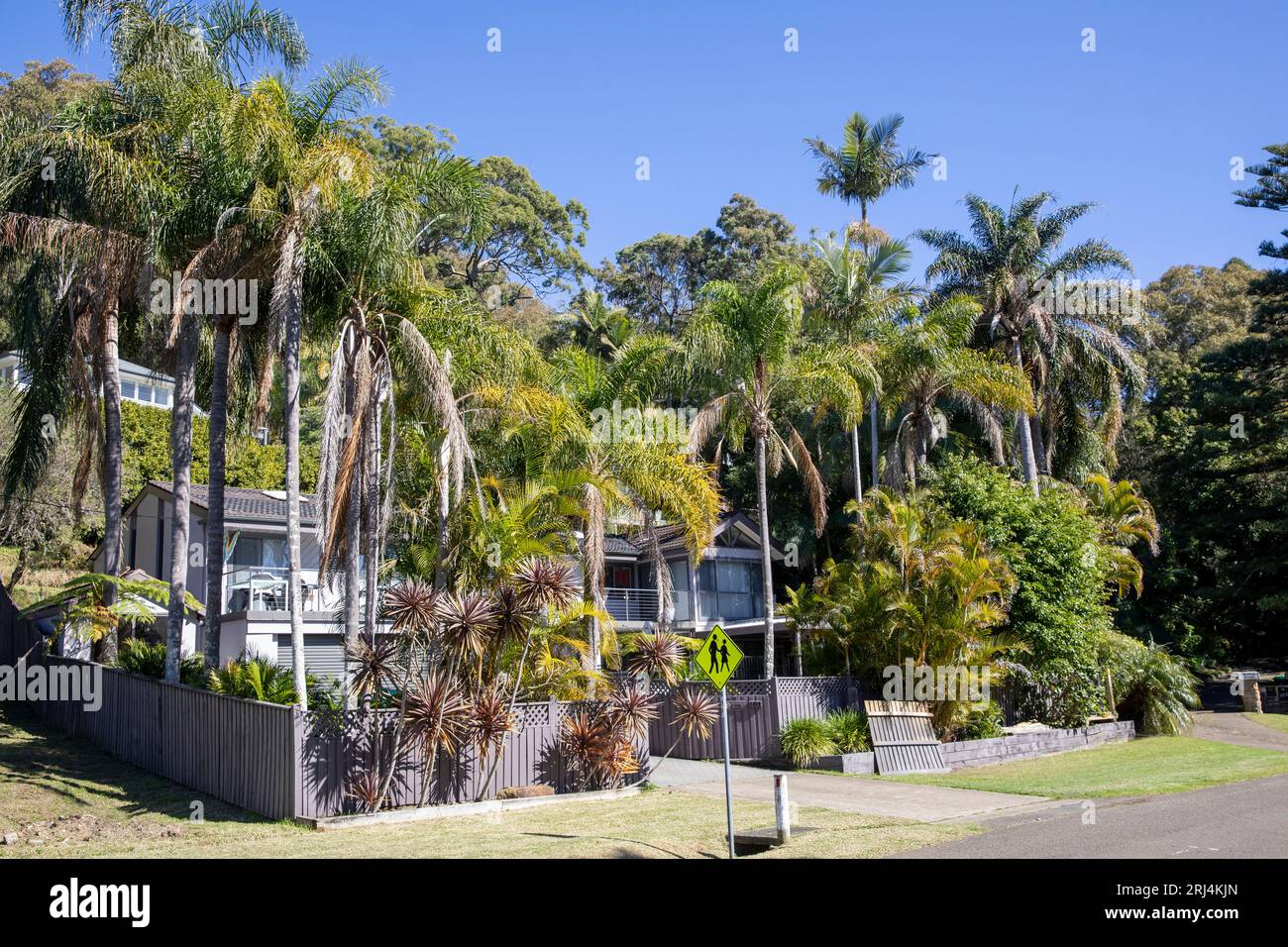 Large detached australian home with lush green garden on blue sky ...