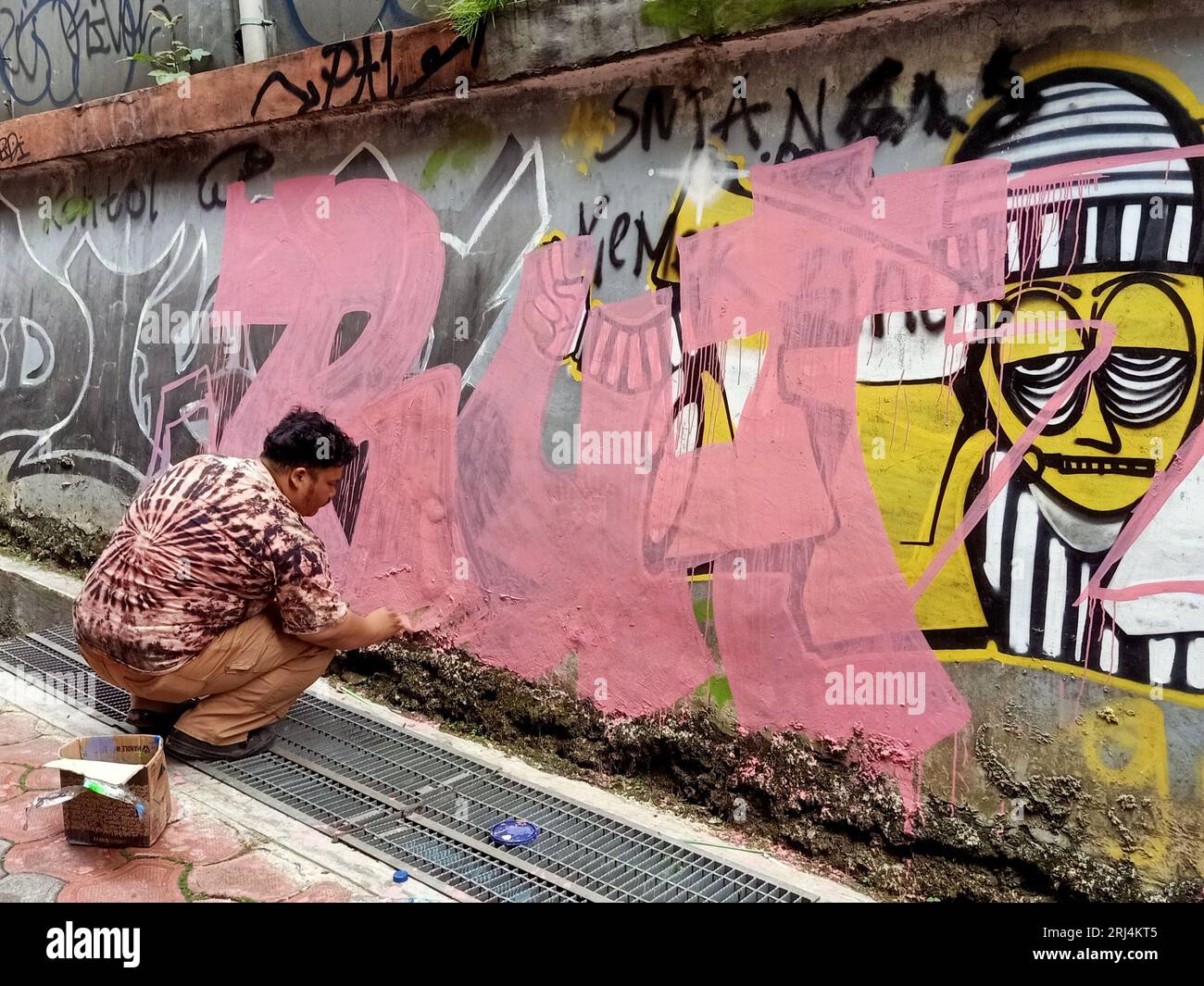 a young man is covering the graffiti on the wall with his newest mural ...