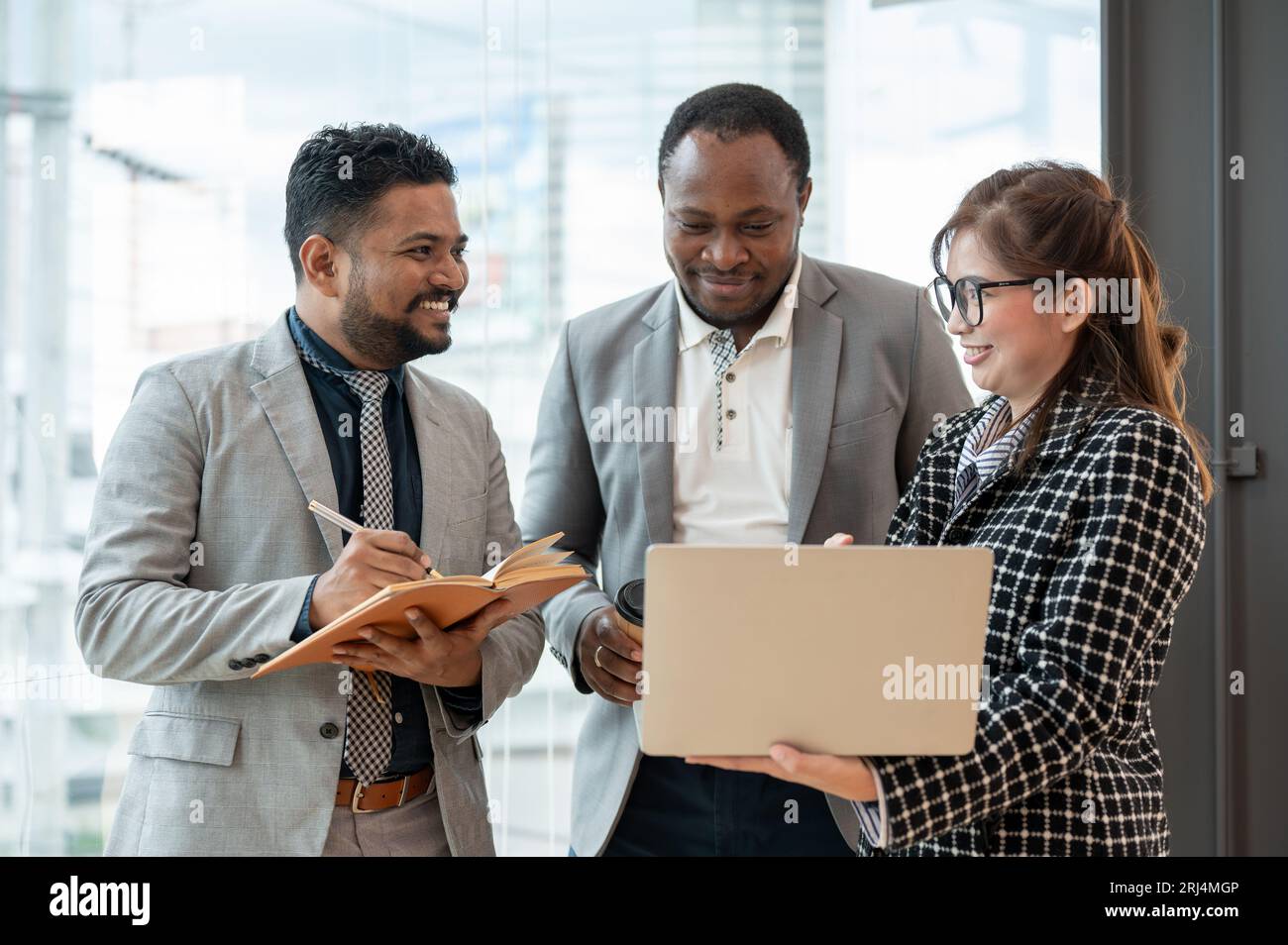 A multiracial group of business people is discussing work while ...