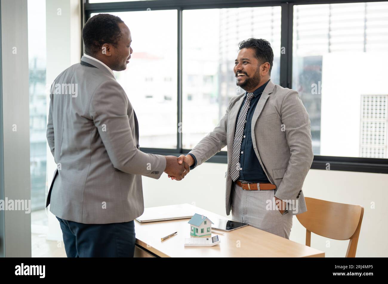 A professional Indian-Asian businessman shakes hands with an African ...