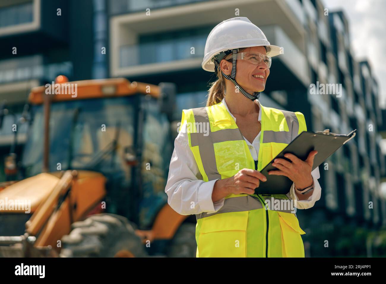 Professional female engineer in protective helmet making notes on ...