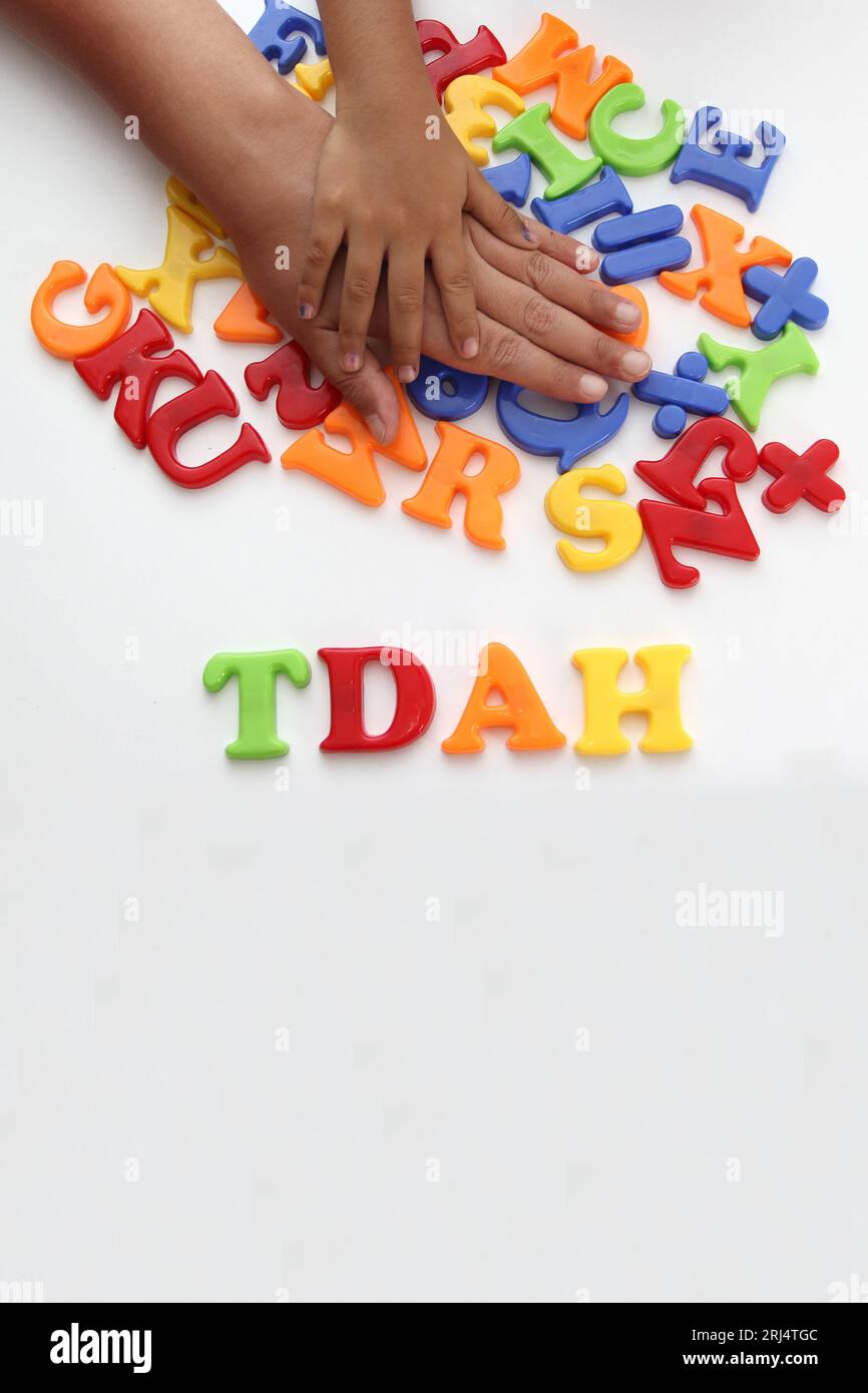 Hands of mom and daughter playing with colored letters that form ADHD ...
