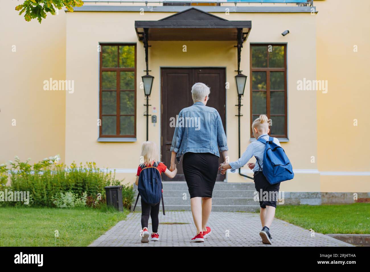 mother accompanies children to school holding hands. Caucasian blond ...