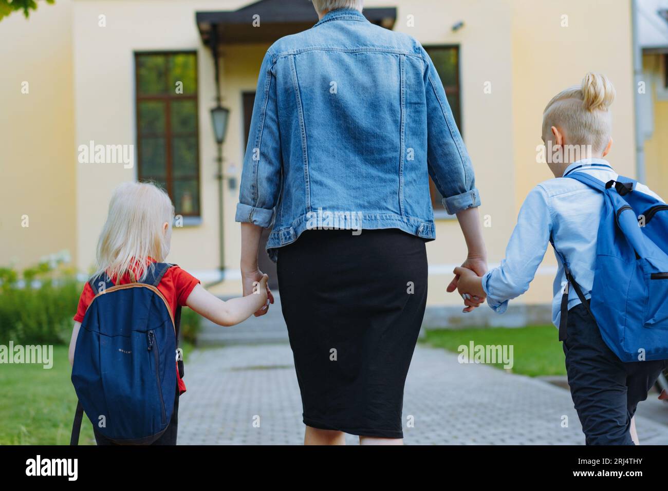 mother accompanies children to school holding hands. Caucasian blond ...