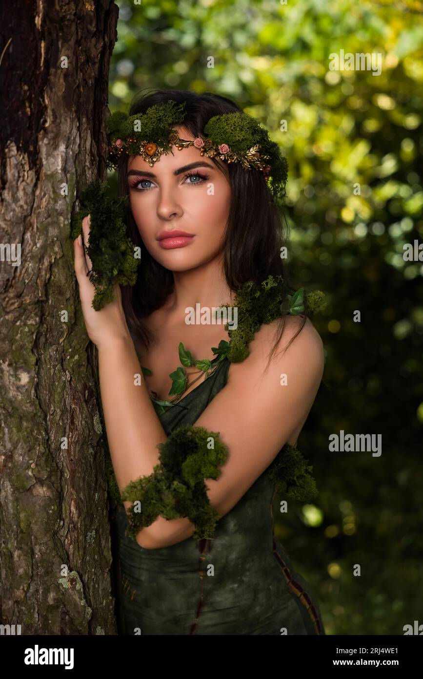 Beautiful young woman in green dress posing as a forest fairy with ...