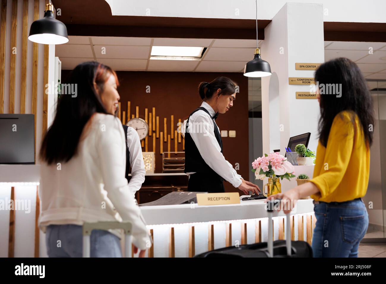 Cozy hotel reception with two female guests waiting for concierge to ...