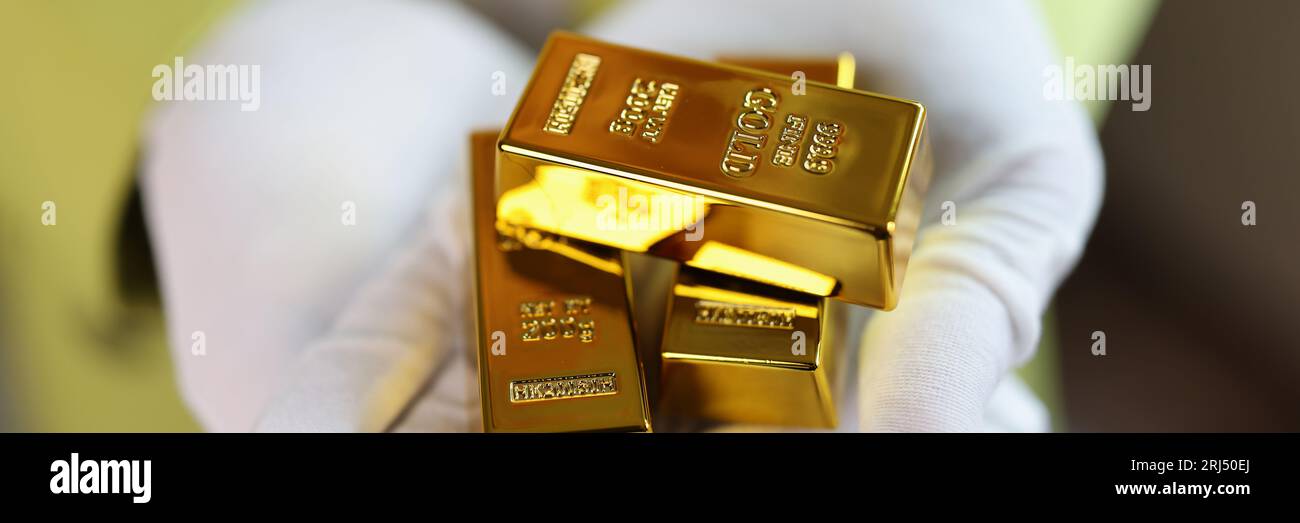 Gold bars in gloved hands close up Stock Photo - Alamy